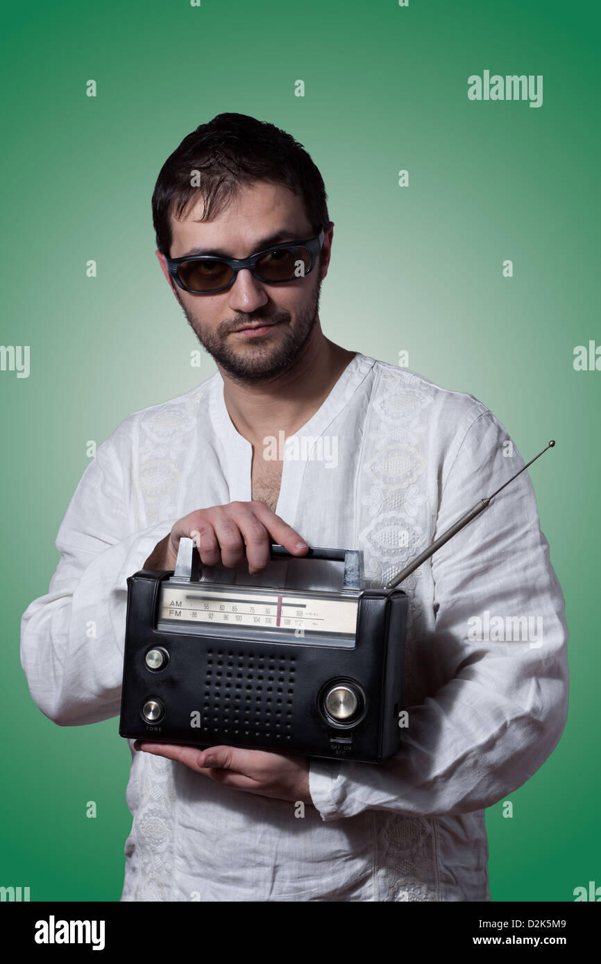 Young bearded man holding a vintage radio on green background Stock ...