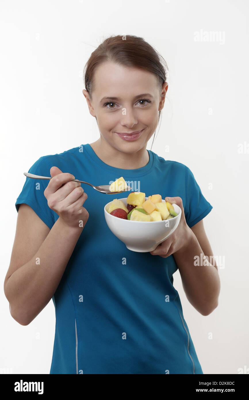 Thoughtful woman eating a fruit salad looking very happy Stock Photo ...