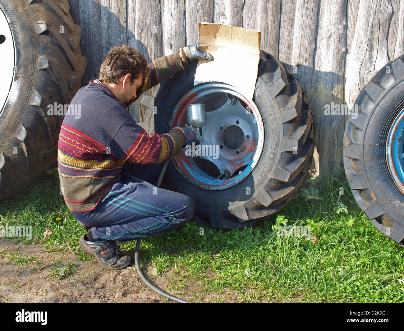 Adult man coloring tractor outdoor with air color sprayer Stock Photo ...