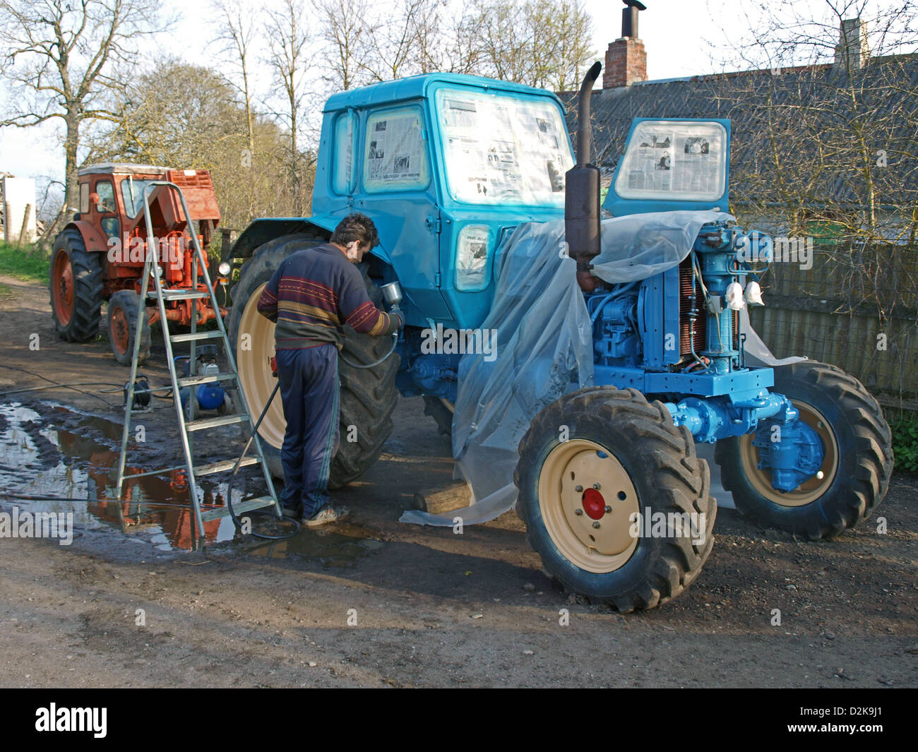 Adult man coloring tractor outdoor with air color sprayer Stock Photo ...