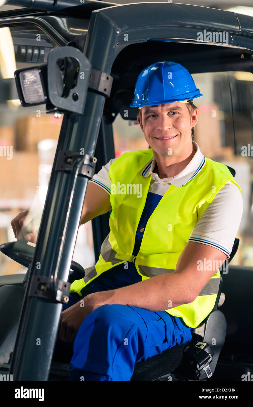 forklift driver in protective vest and forklift at warehouse of freight ...