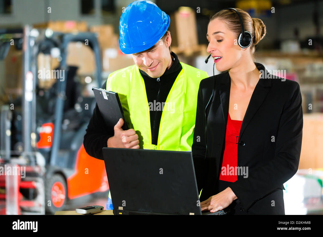 Teamwork - warehouseman or forklift driver and female supervisor with ...