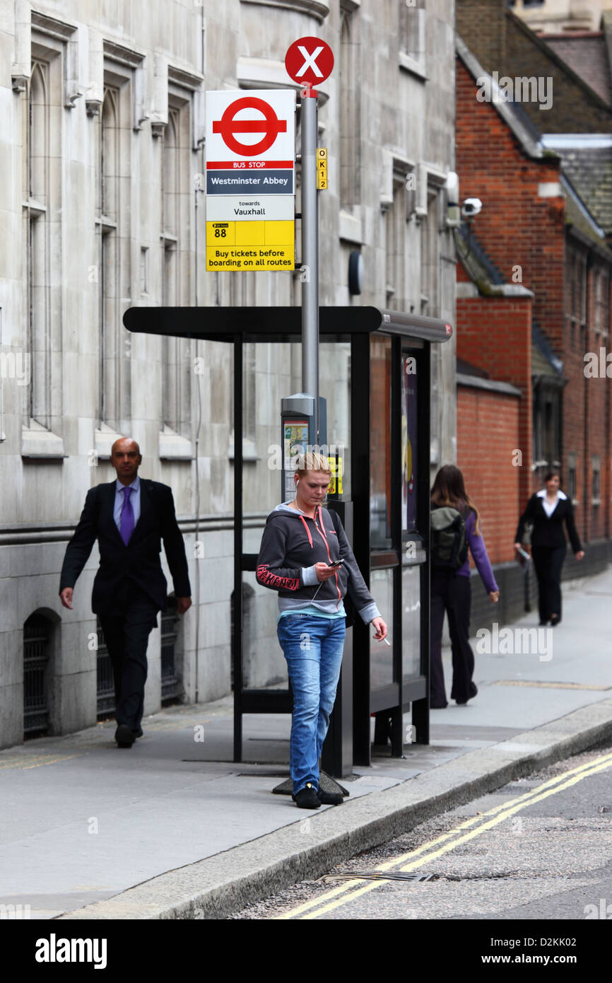Girl sending text message from mobile phone while waiting at bus stop ...