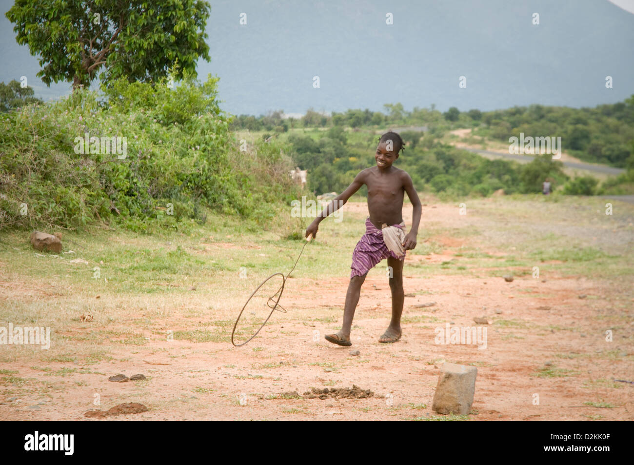 Benna boy running and playing in field with large hoop Stock Photo - Alamy