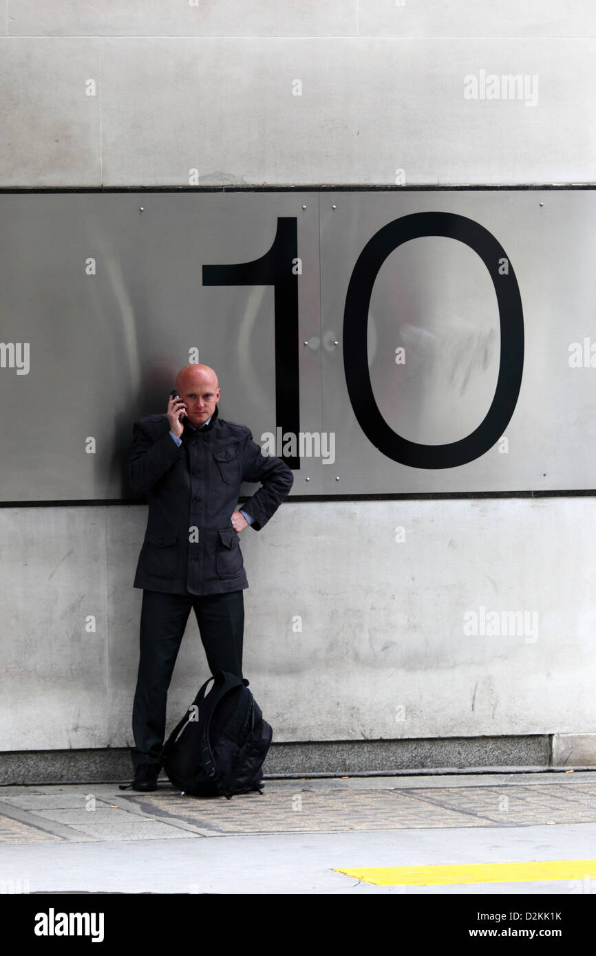 Man talking on mobile phone next to number 10 (ten) figure, London ...