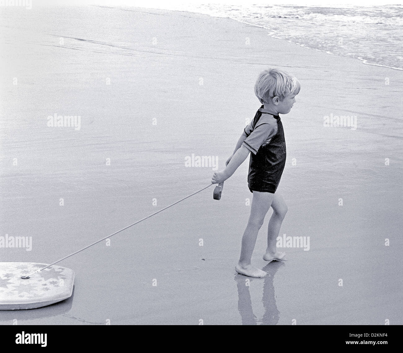 Small boy dragging bodyboard towards sea Stock Photo - Alamy