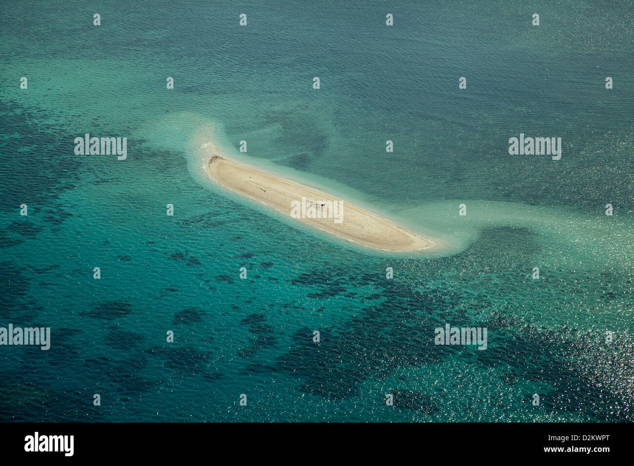 Aerial overlooking a sand island and the marine coral systems of sea at ...