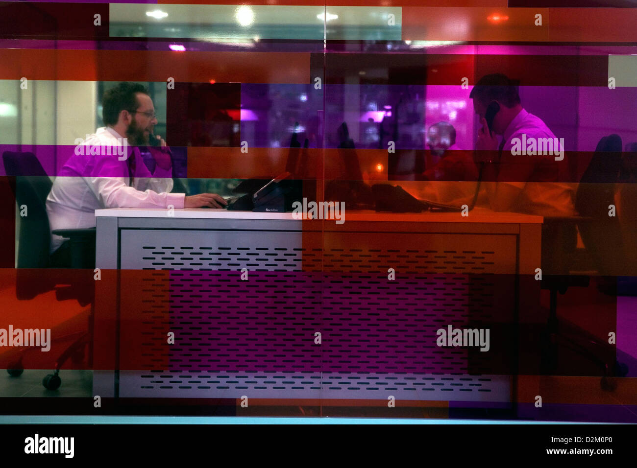 Men sit behind a colored screen working at their desks at a company ...