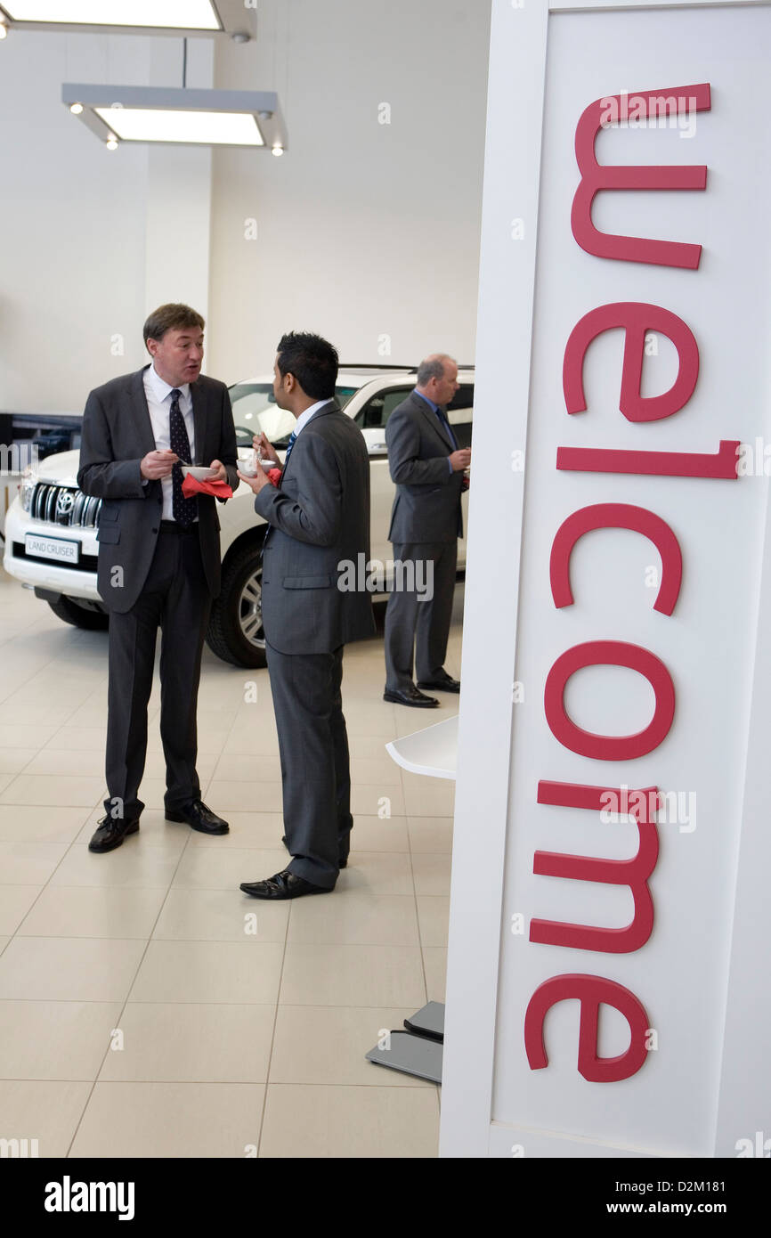 Businessmen stand behind a large welcome sign in a newly opened Toyota ...