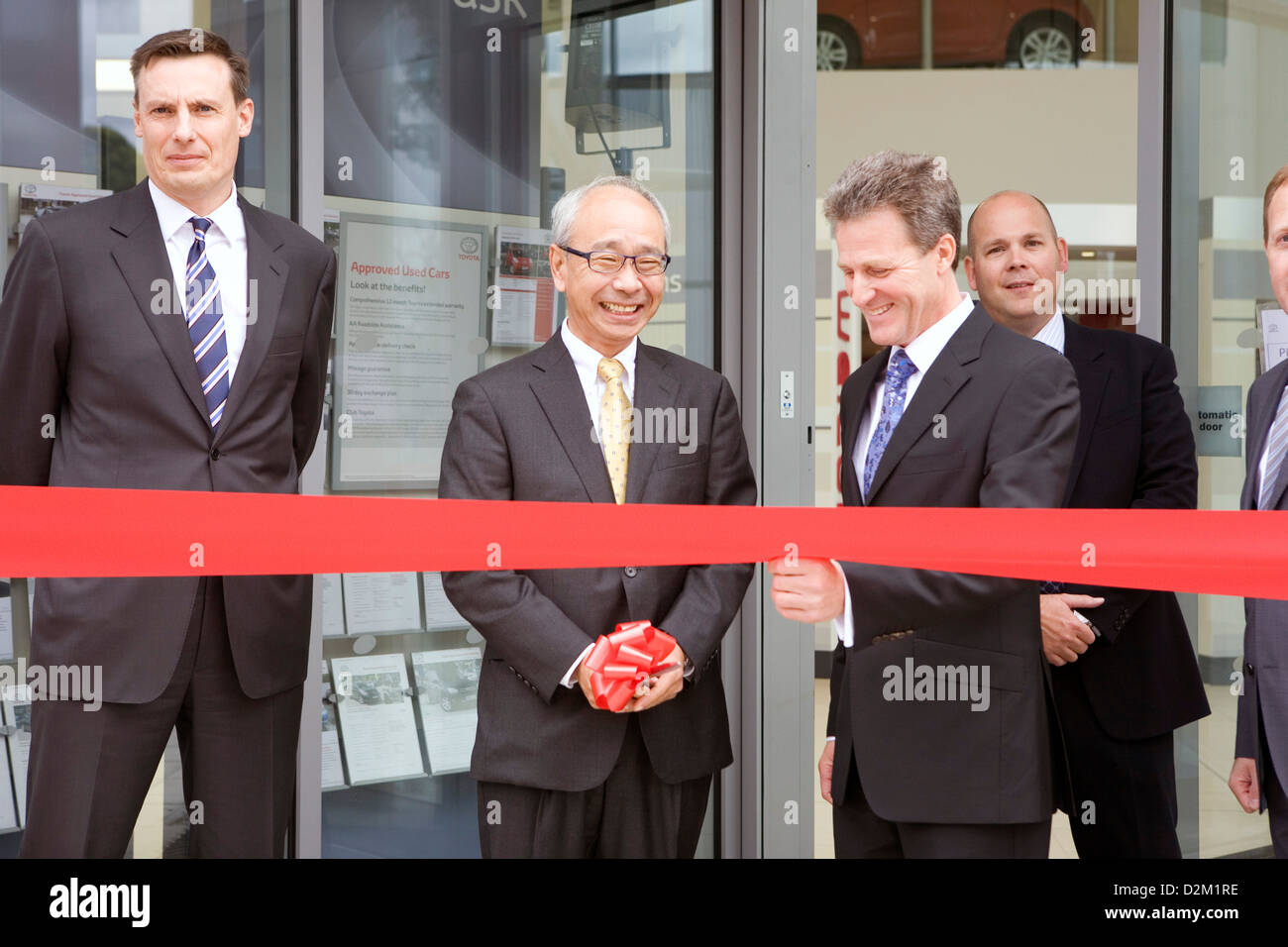 Businessmen gather to cut the red tape and officially open a new car ...