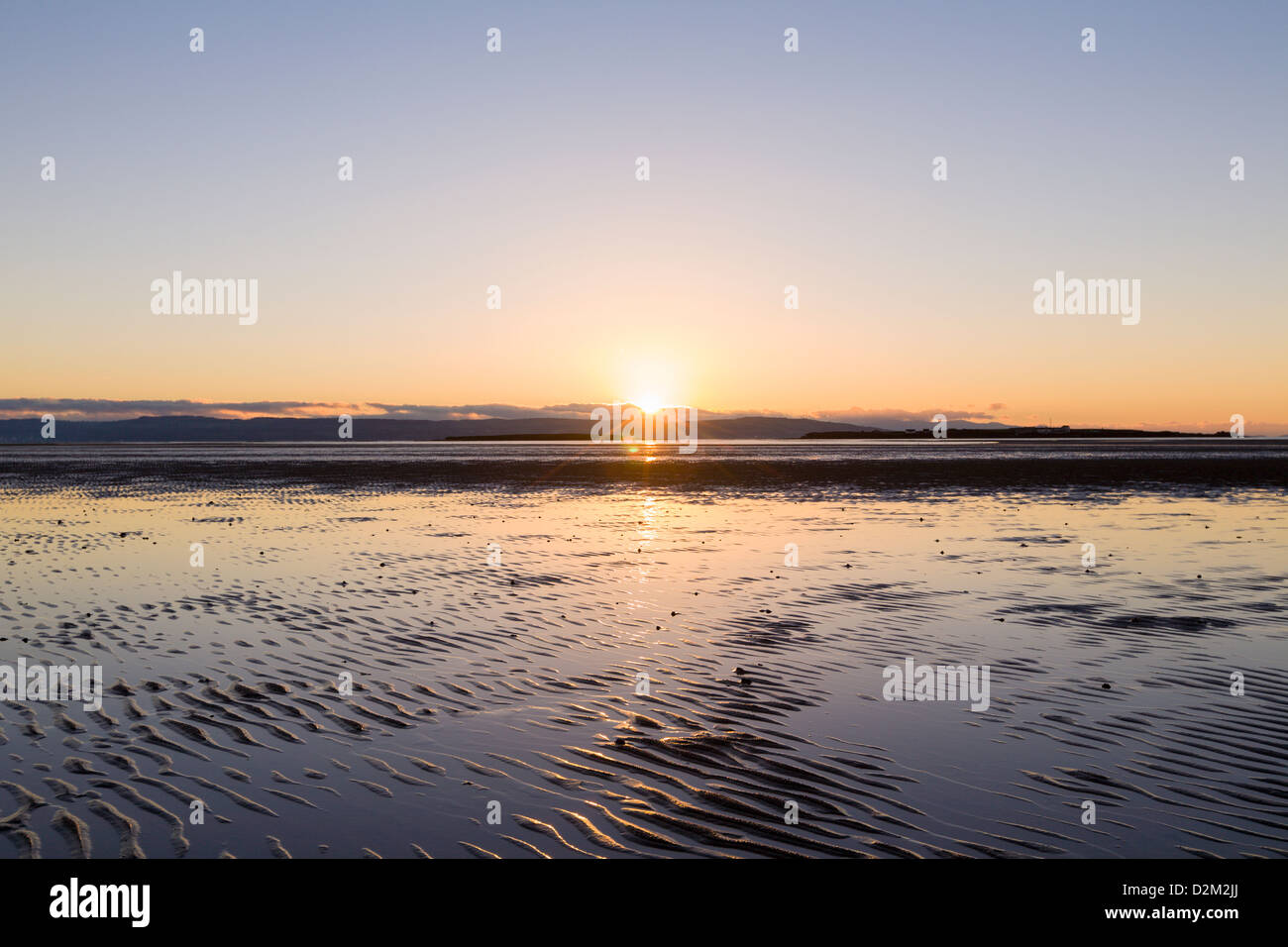 Sun setting over sandy beach Stock Photo - Alamy