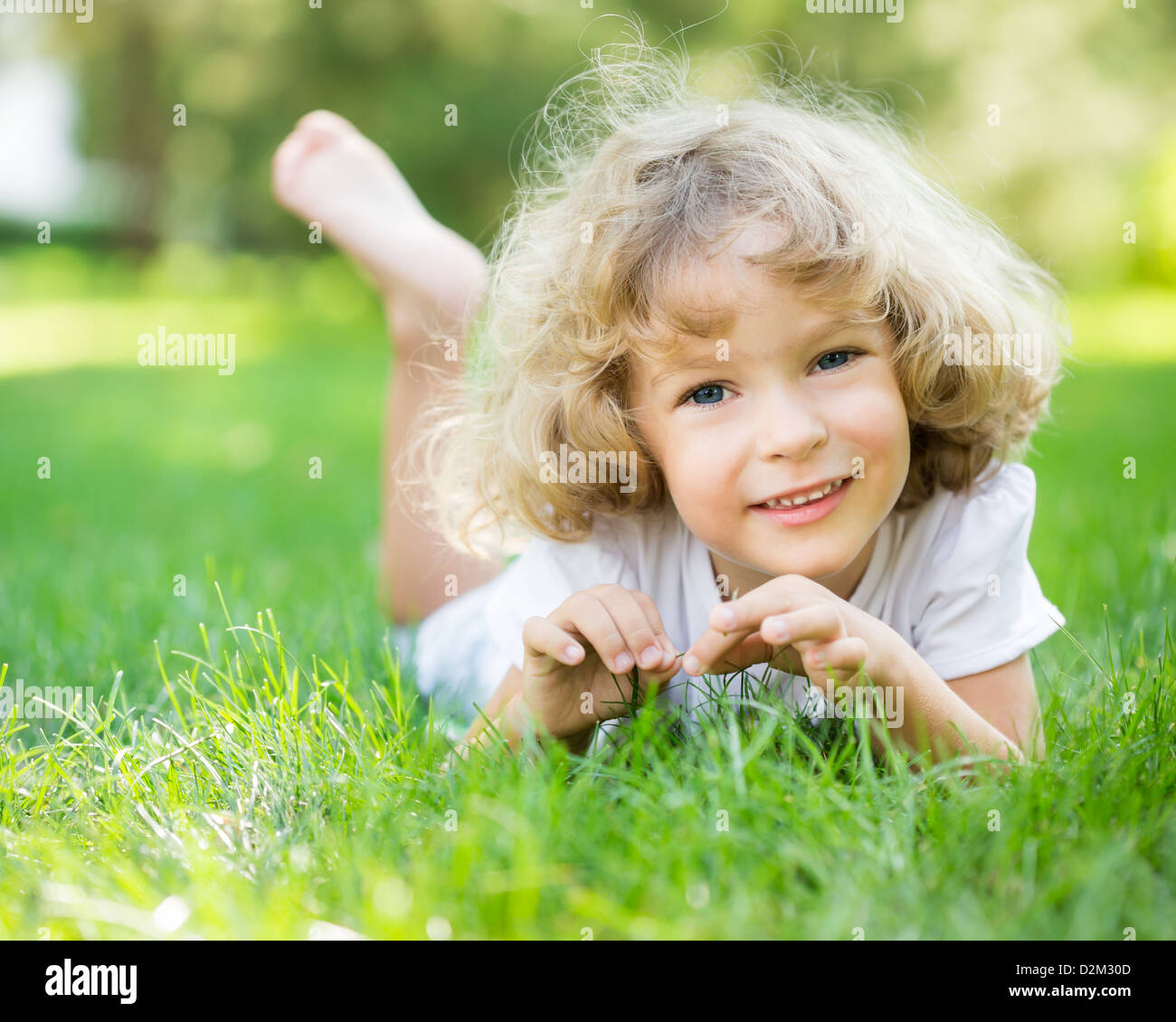 Happy child playing on green grass in spring park Stock Photo - Alamy