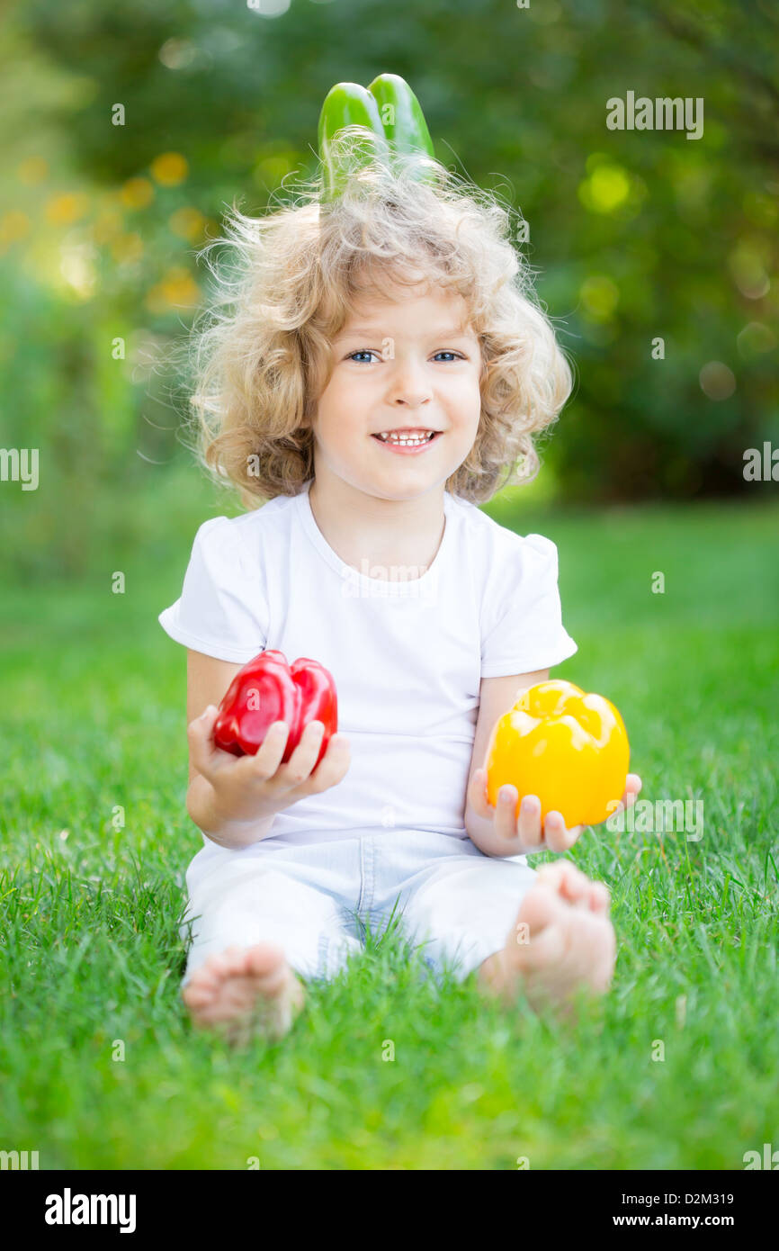 Happy smiling child with vegetables sitting on green grass in spring ...