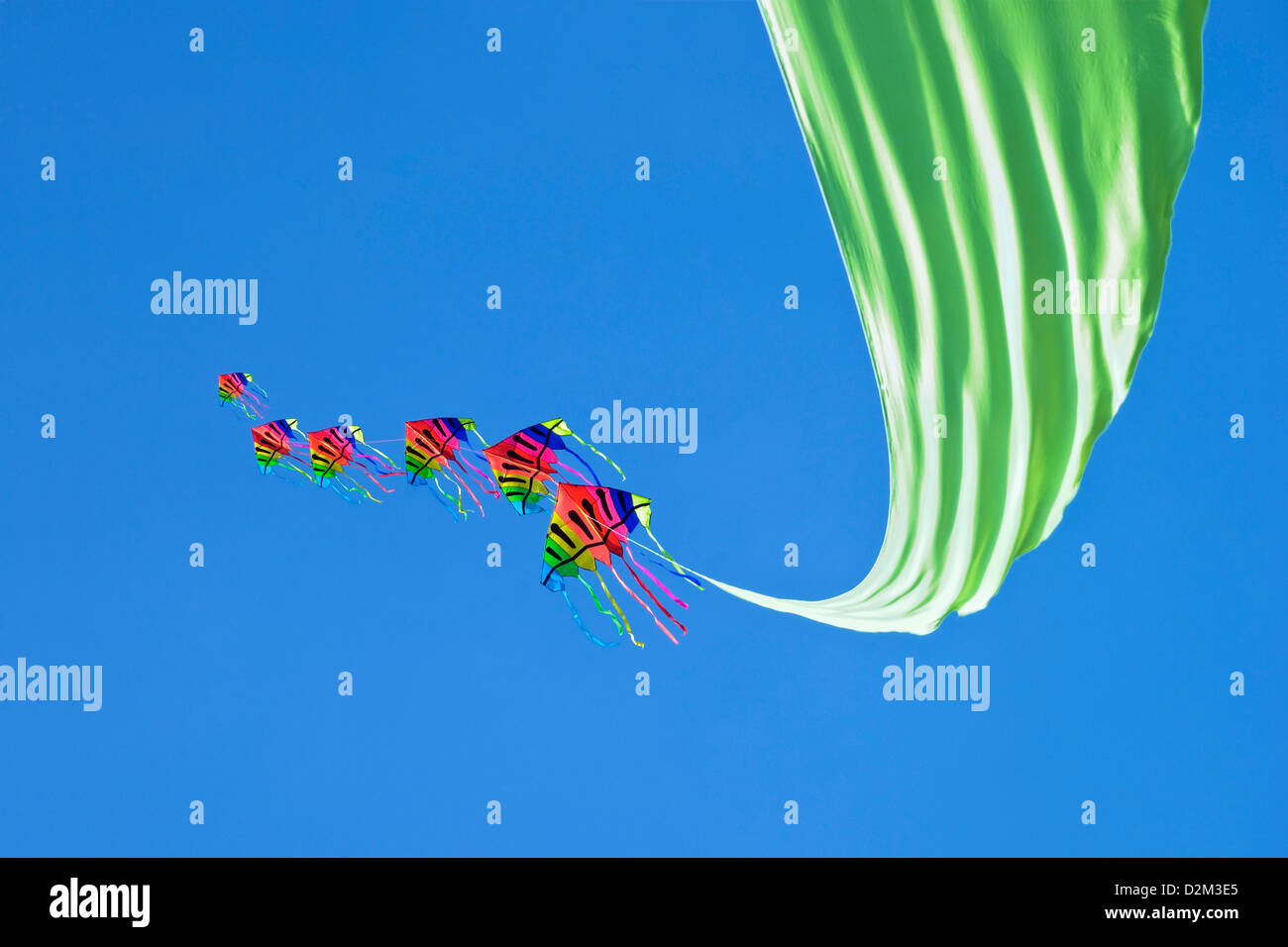 A very colourful kite with six heads and a long, lime green ribbon ...