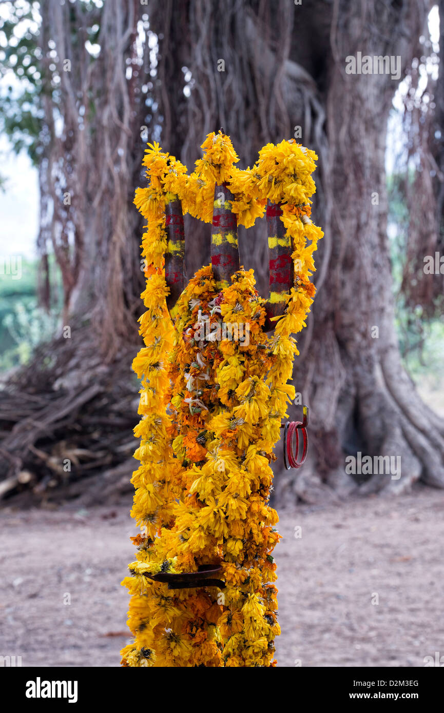 Decorative flower garlanded trident in front of a hindu temple. Andhra ...