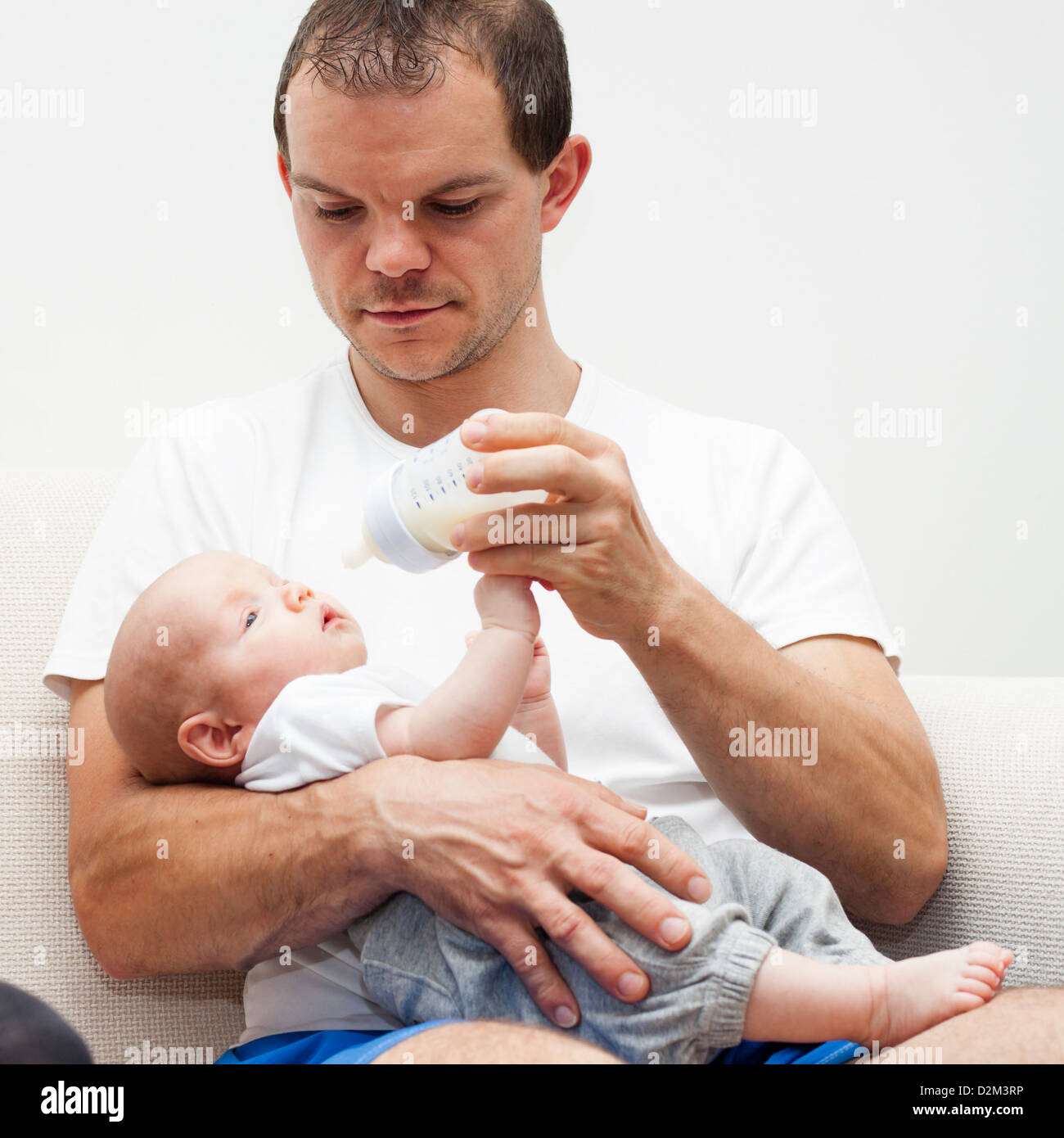 Portrait of man feeding cute baby boy Stock Photo - Alamy