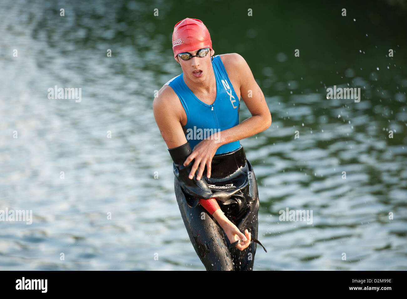First swimmer out of transition running and taking off wetsuit with ...