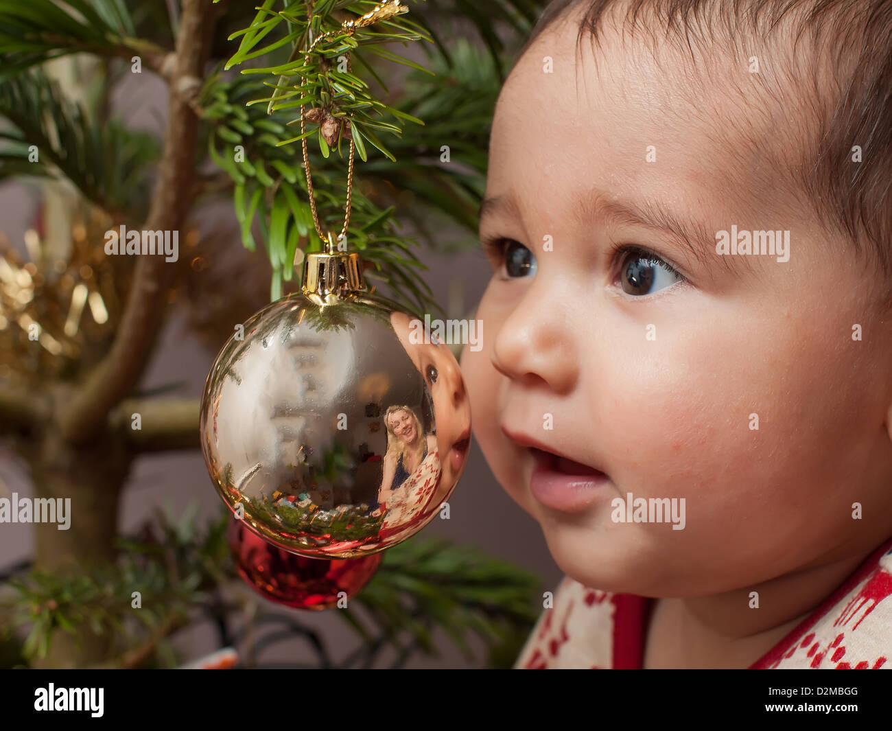 6 month old baby looking at reflection in Christmas bauble, mother's ...