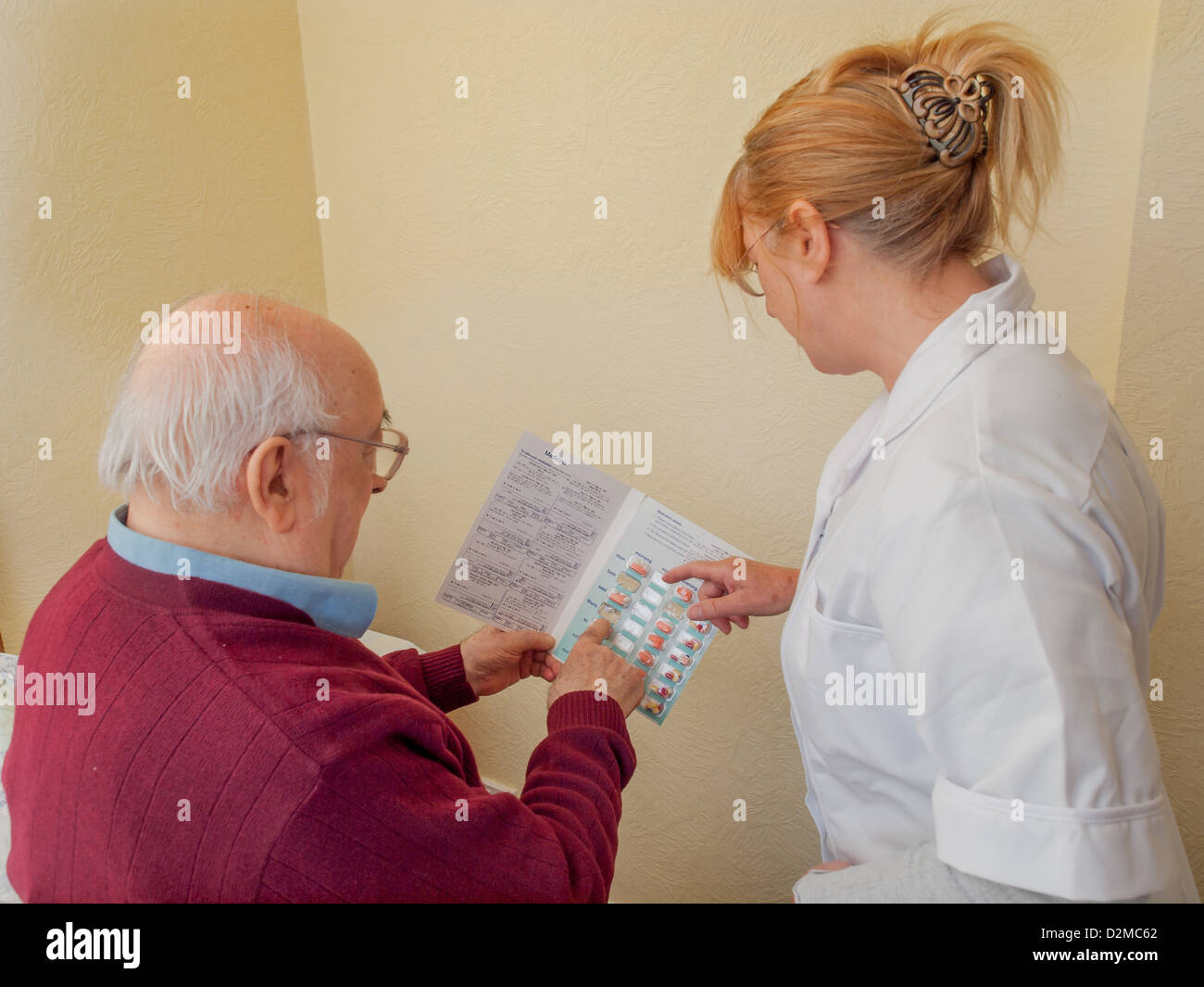 Carer being shown medication by elderly gentleman Stock Photo - Alamy