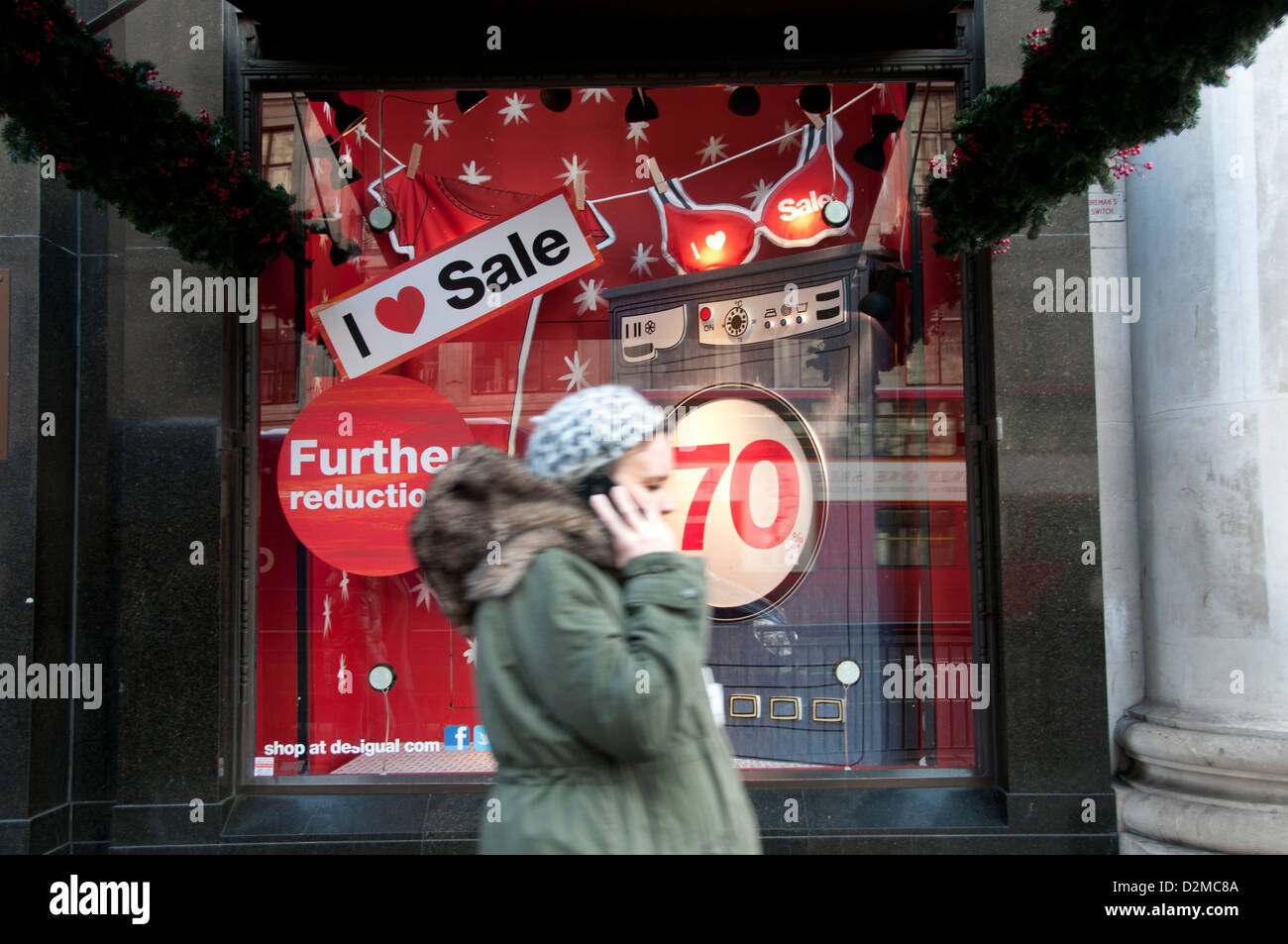 London sales. Woman talking on a mobile phone walks past a shop with ...