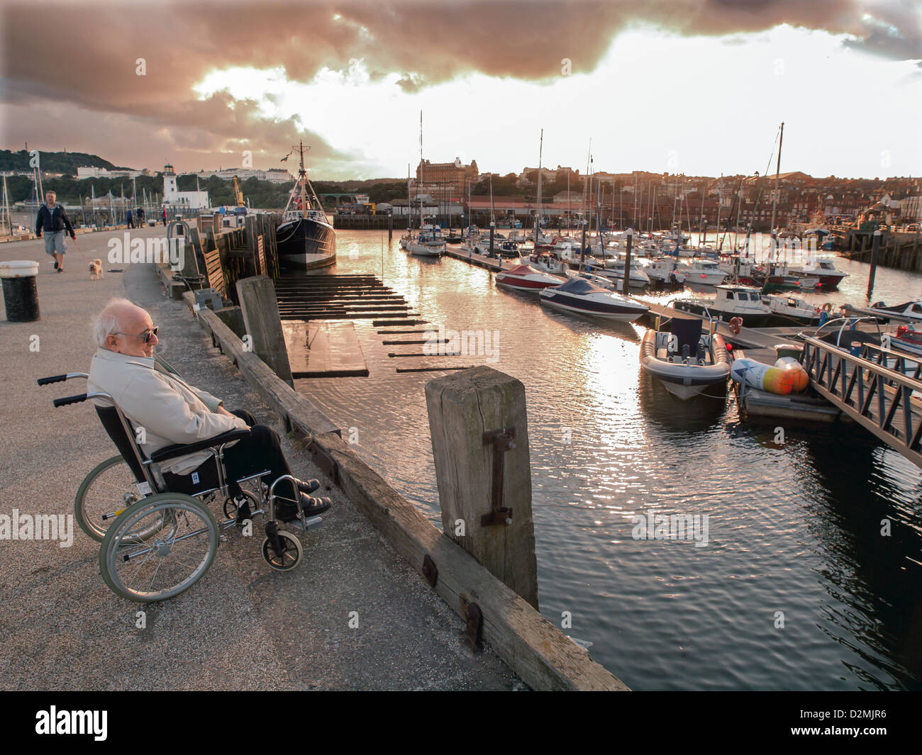 elderly man sitting in wheelchair looking at boats in harbour harbor ...