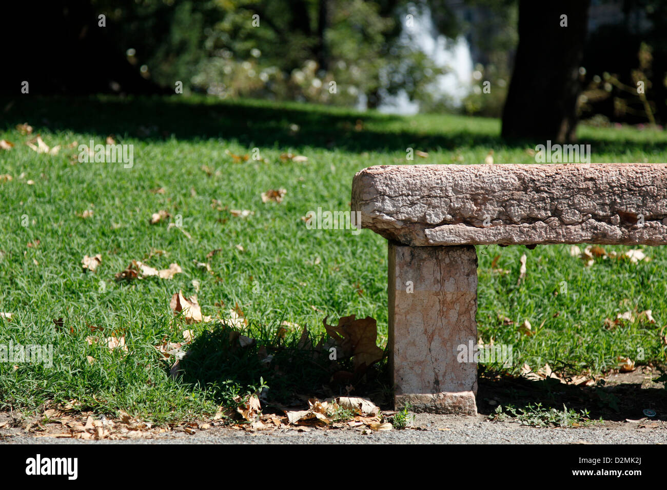 A stone bench in a park near a green grass lawn Stock Photo - Alamy