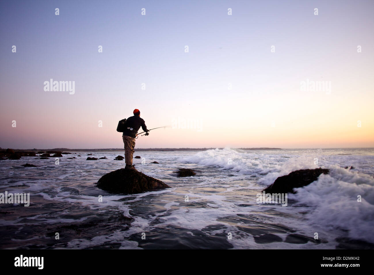 An angler casts his line into the Atlantic at sunrise, embracing the ...