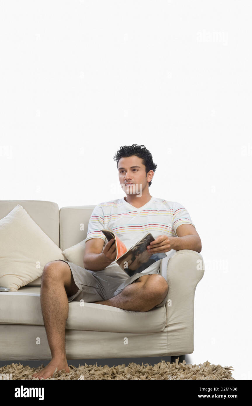 Man holding a magazine on a couch Stock Photo - Alamy