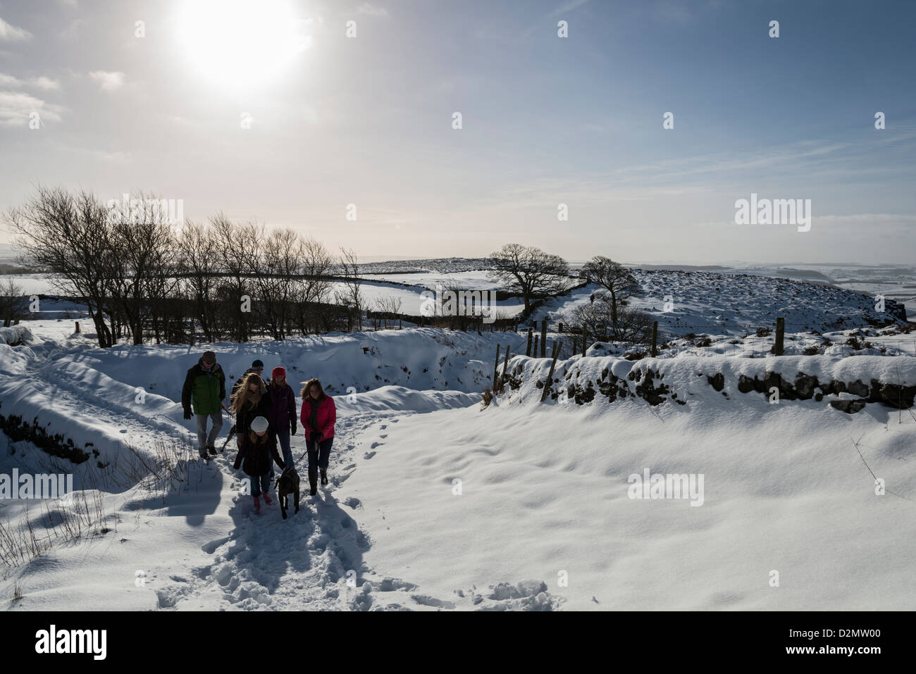 Family group walking and enjoying the snowy weather on Curbar Edge Peak ...
