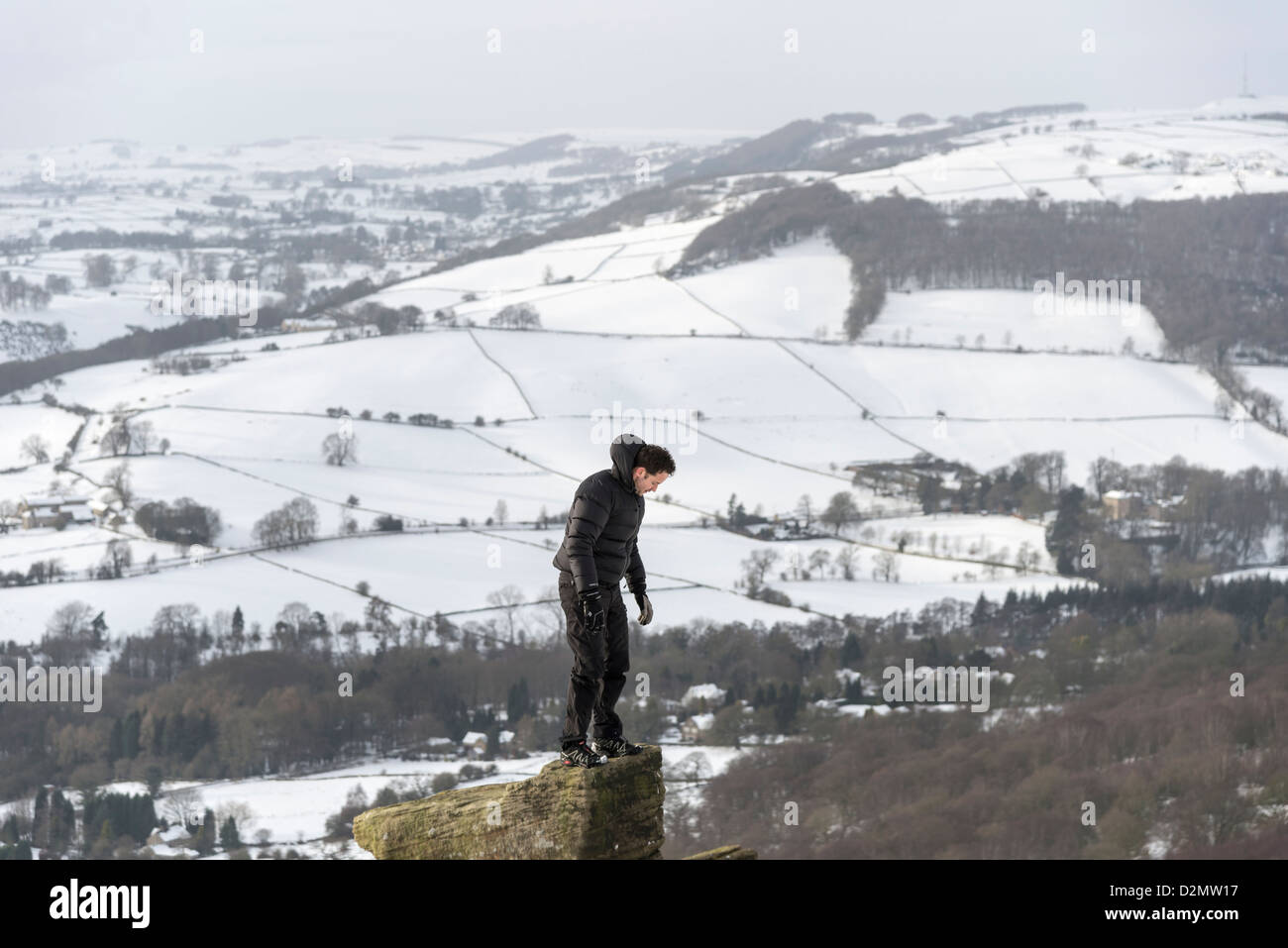person standing on large rock in the snowy weather on Curbar Edge in ...