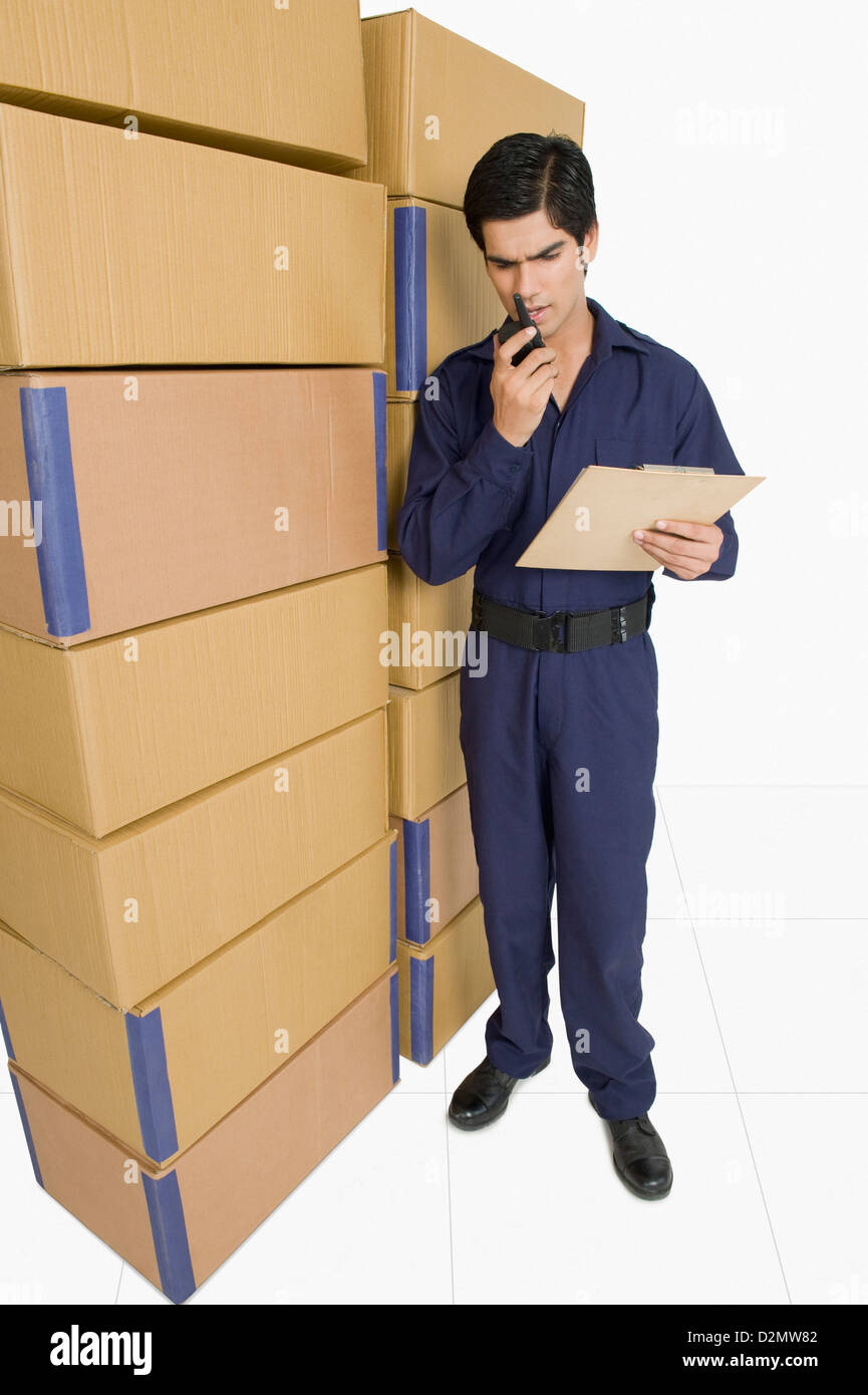 Store incharge talking on a walkie-talkie and examining a document ...