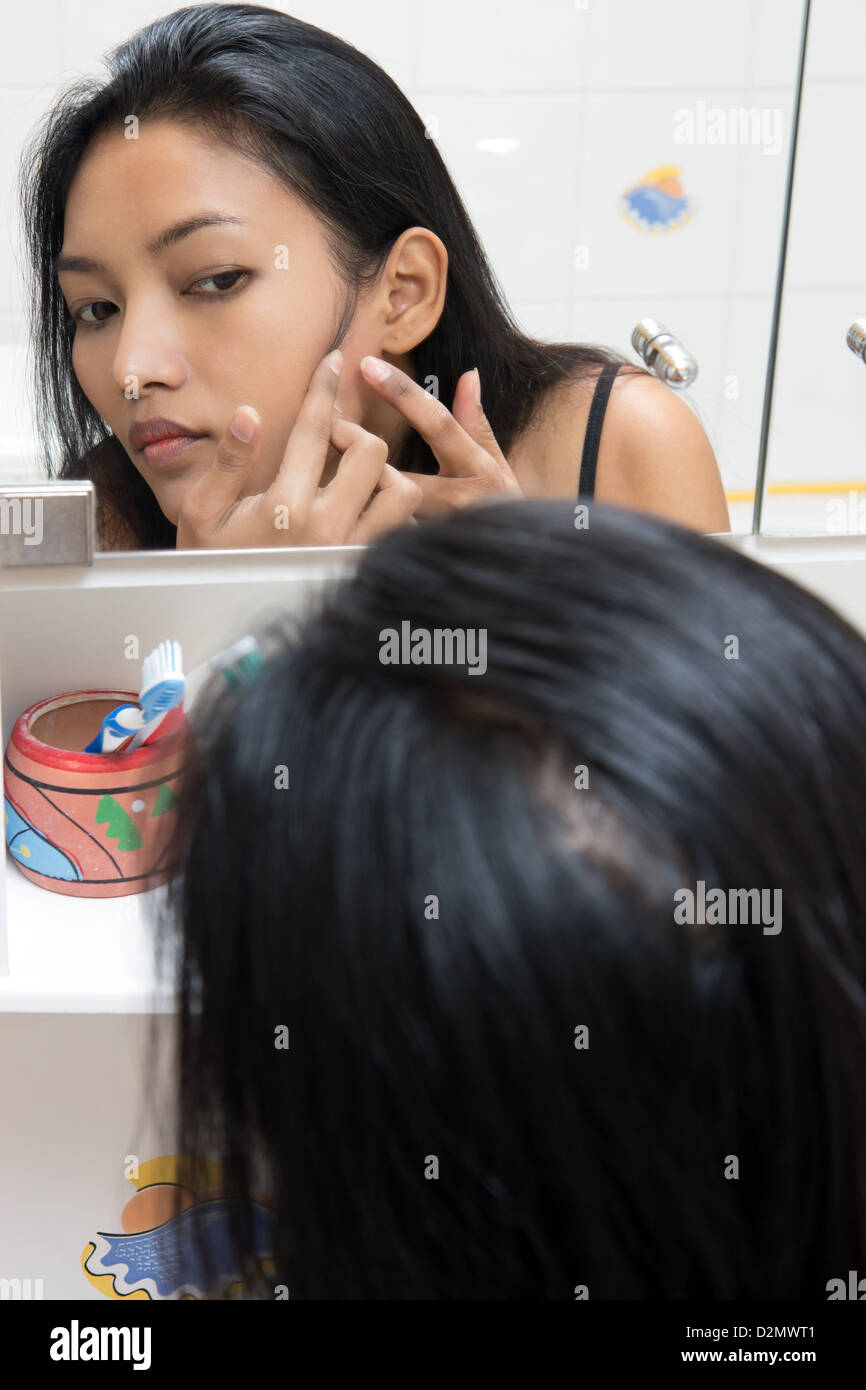 Woman looking at her reflection in the mirror Stock Photo - Alamy