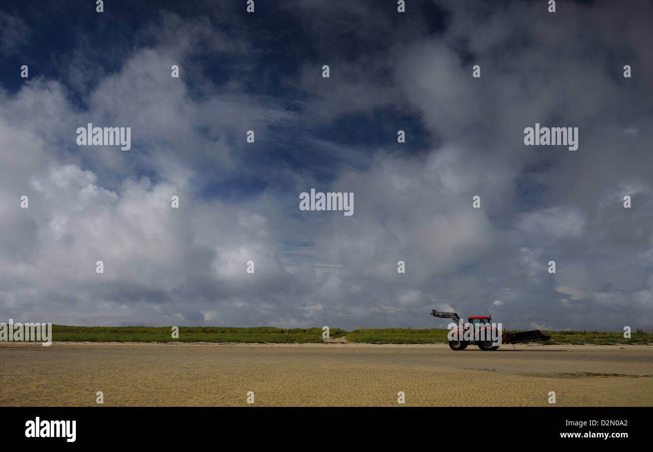 A Red tractor being driven on the beach at North Uist in the Outer ...