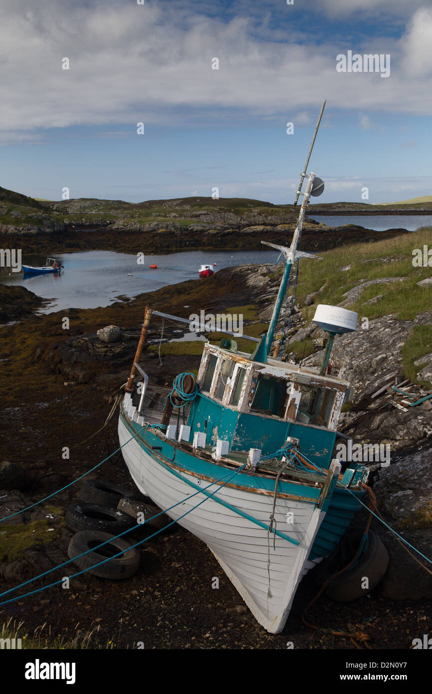 Old fishing boat on the rocks with the tide out on the Isle of Barra in ...