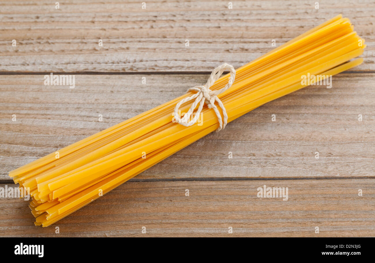 Bundled dried tagliatelle pasta on wooden table Stock Photo - Alamy