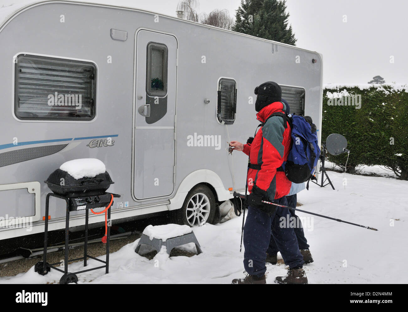 Couple in suitable winter clothes returning to their caravan in an all ...