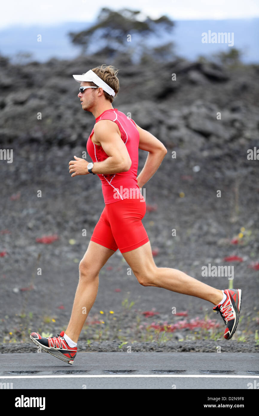 Full length side view of young Male athlete running in red compression ...