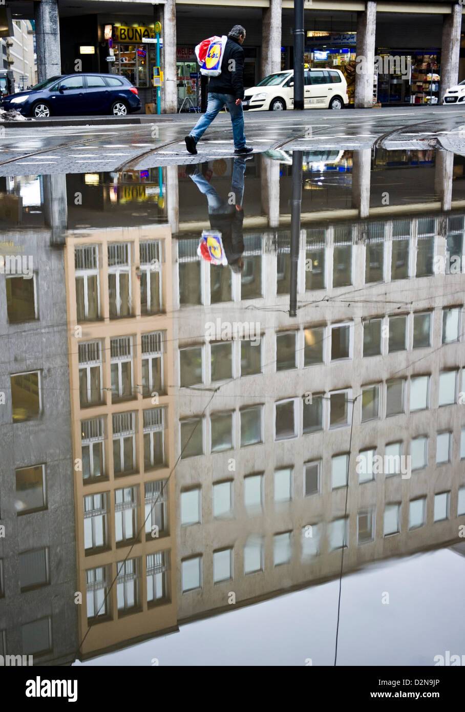 A man walks past a puddle at the base of Tower 185 in Frankfurt Main ...