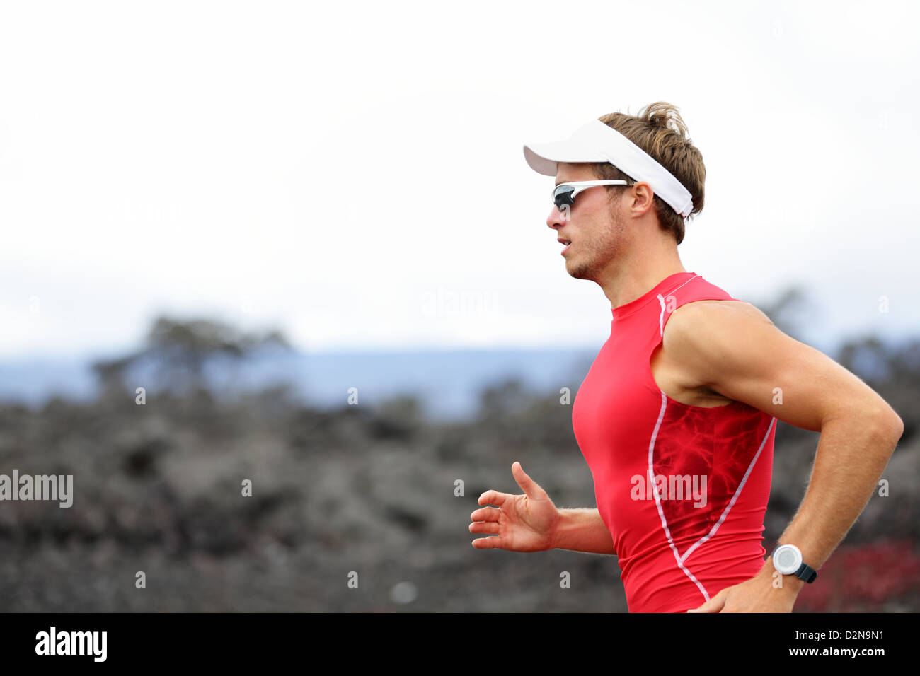 Young Male athlete running in red compression top on volcano in Kailua ...
