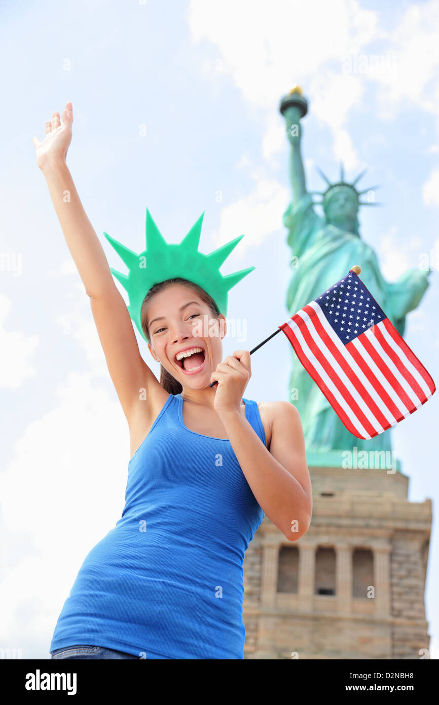 Joyful multiracial woman standing with American flag at Statue of ...