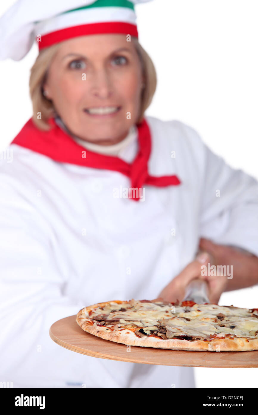 55 years old female pizza cook using a spade and wearing uniform pizza ...