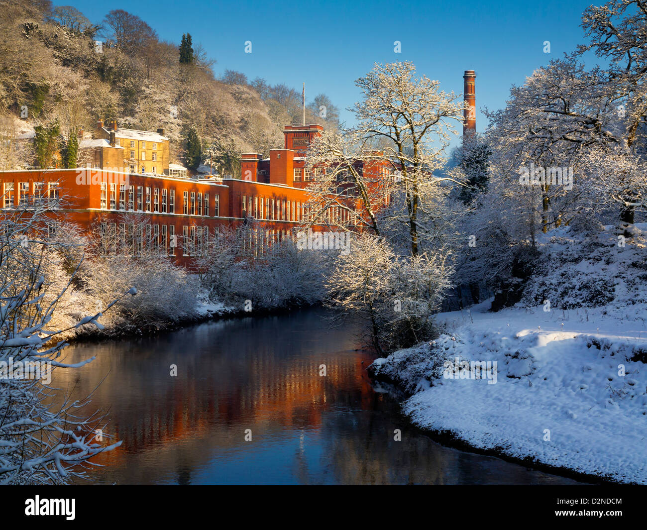Masson Mill and River Derwent in winter sunshine with snow and blue sky ...