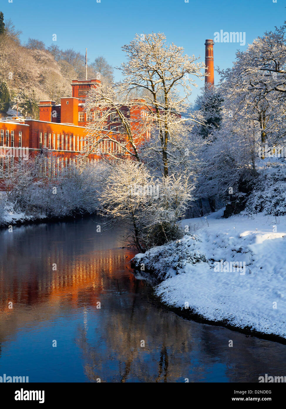 Masson Mill and River Derwent in winter sunshine with snow and blue sky ...
