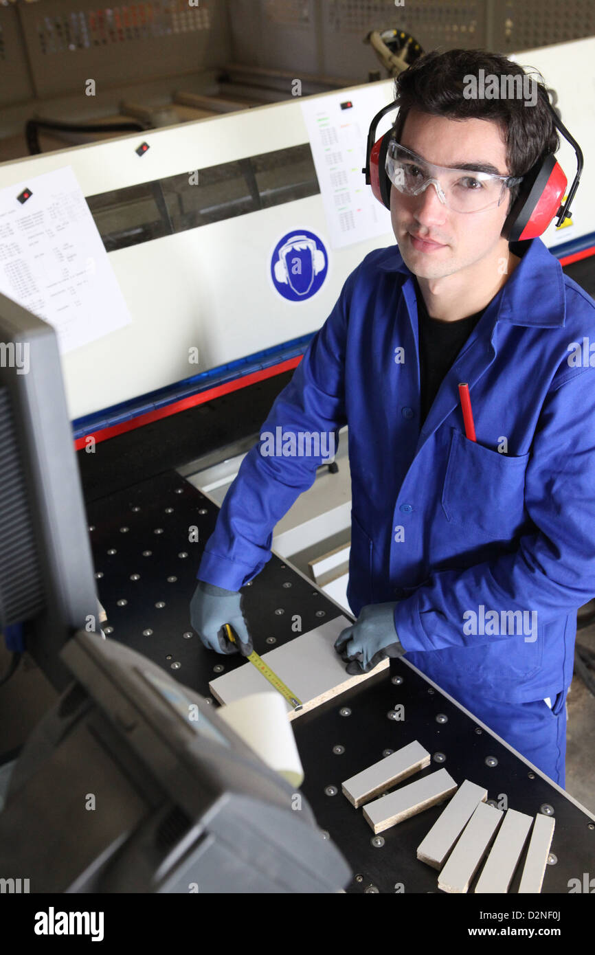 Young factory worker operating cutting machine Stock Photo - Alamy