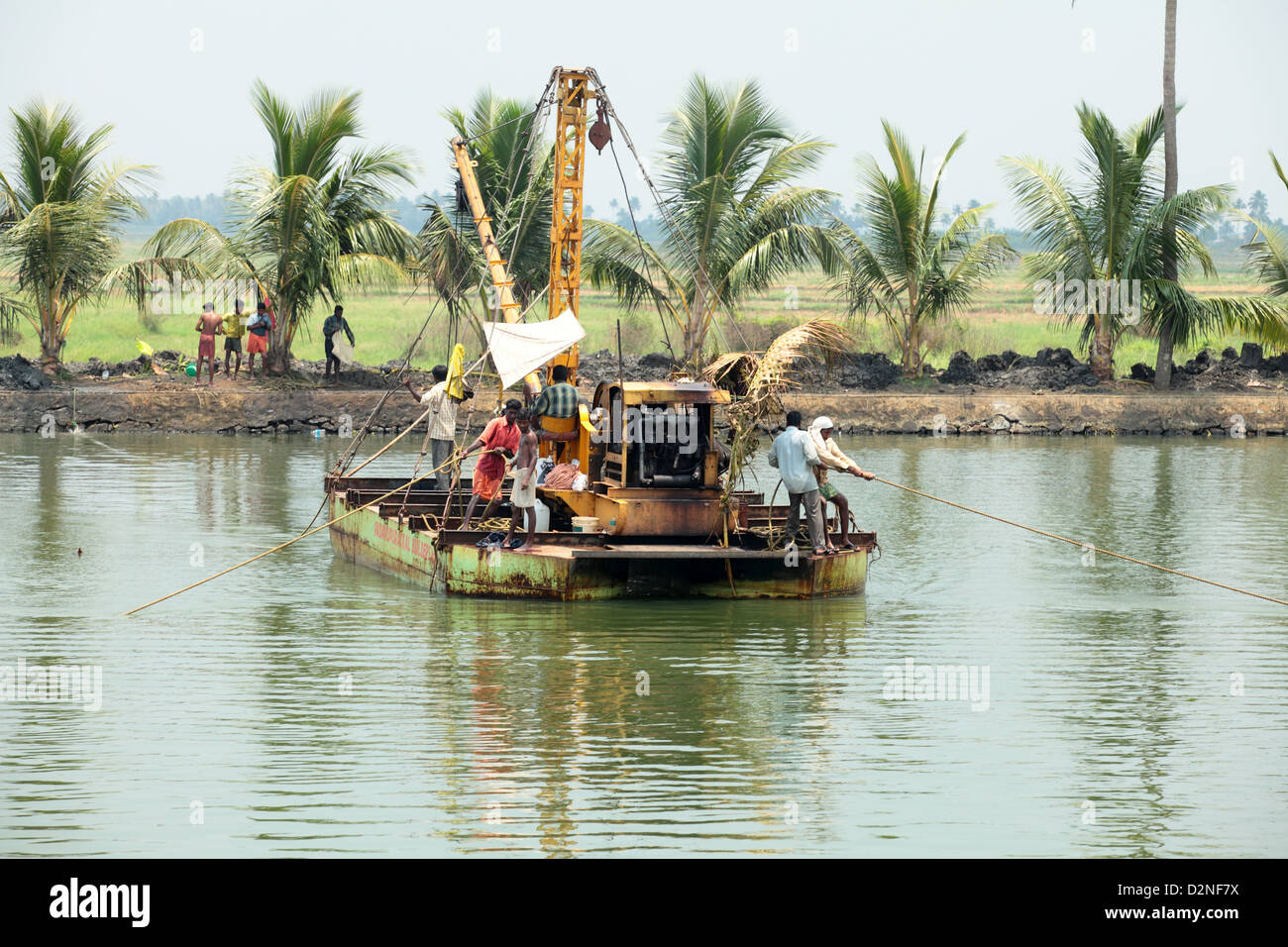 Workers manoeuvre dredging equipment on the Kerala backwaters, in the ...