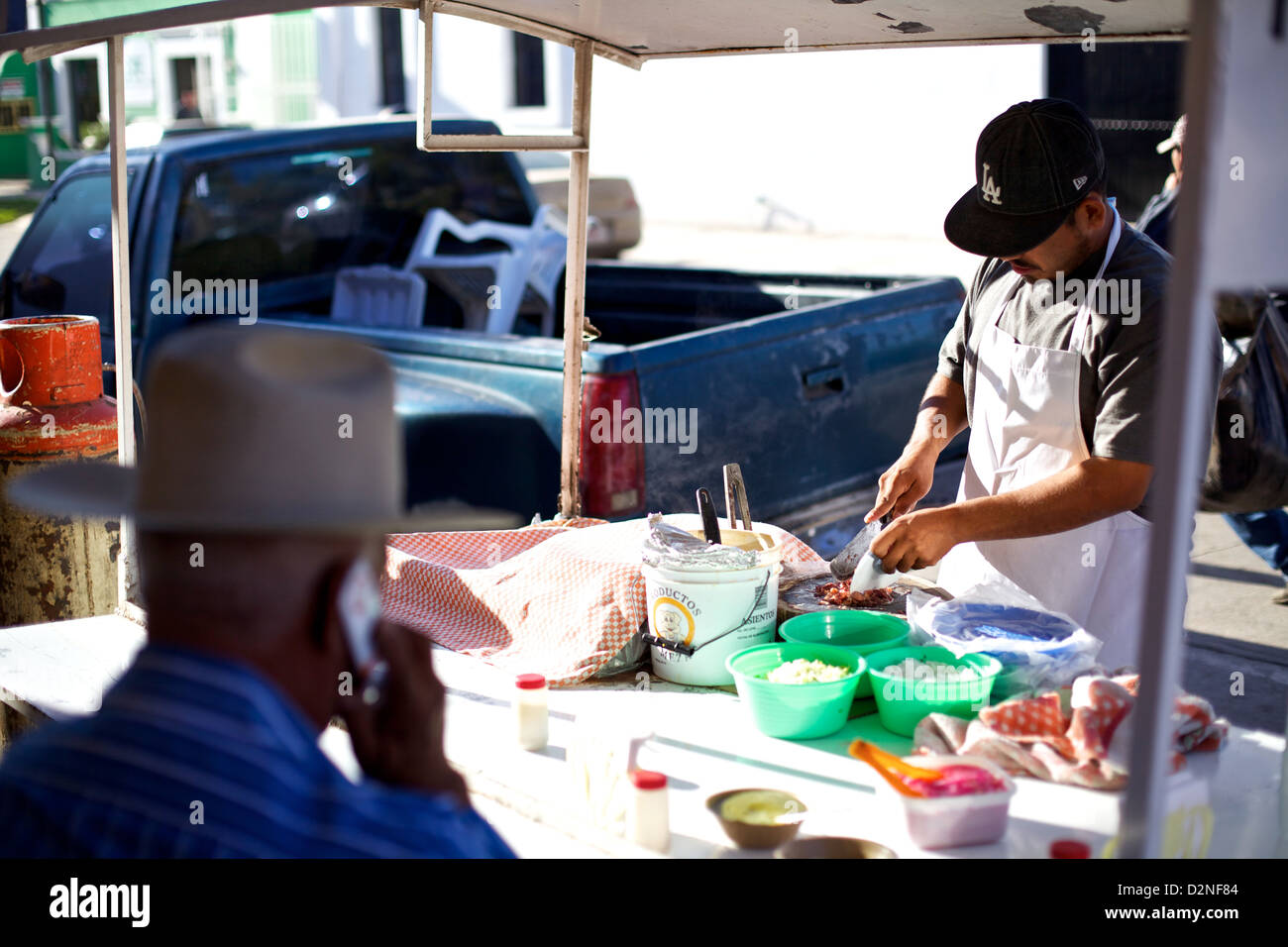 A young cook prepares beef tacos from his street cart in Mazatlan ...