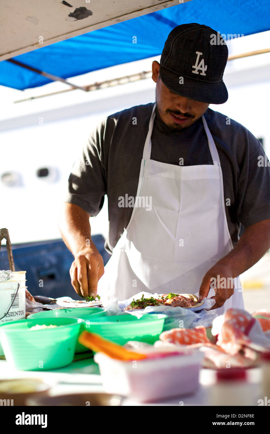 A young cook prepares beef tacos from his street cart in Mazatlan ...