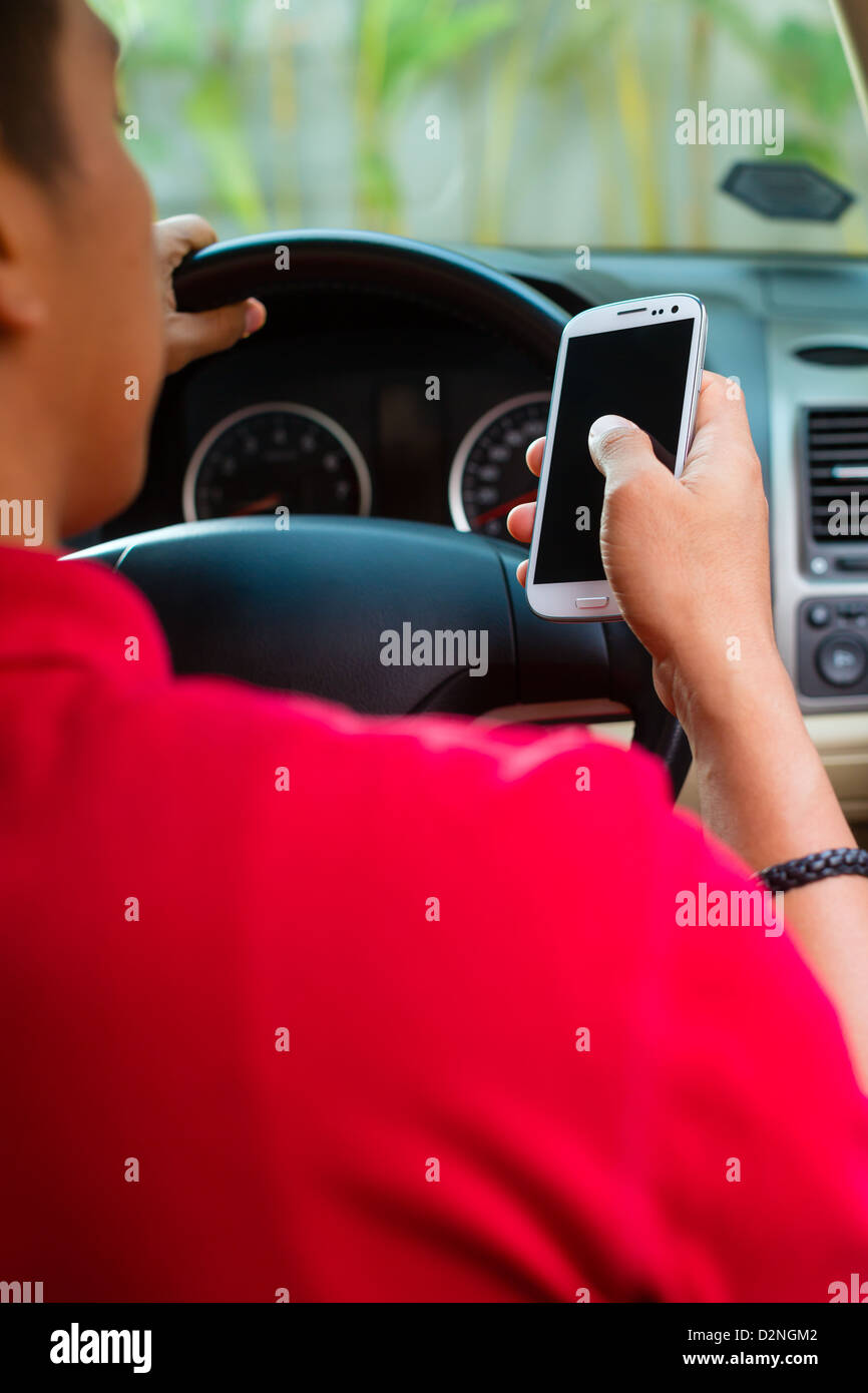 Asian man texting while driving Stock Photo - Alamy