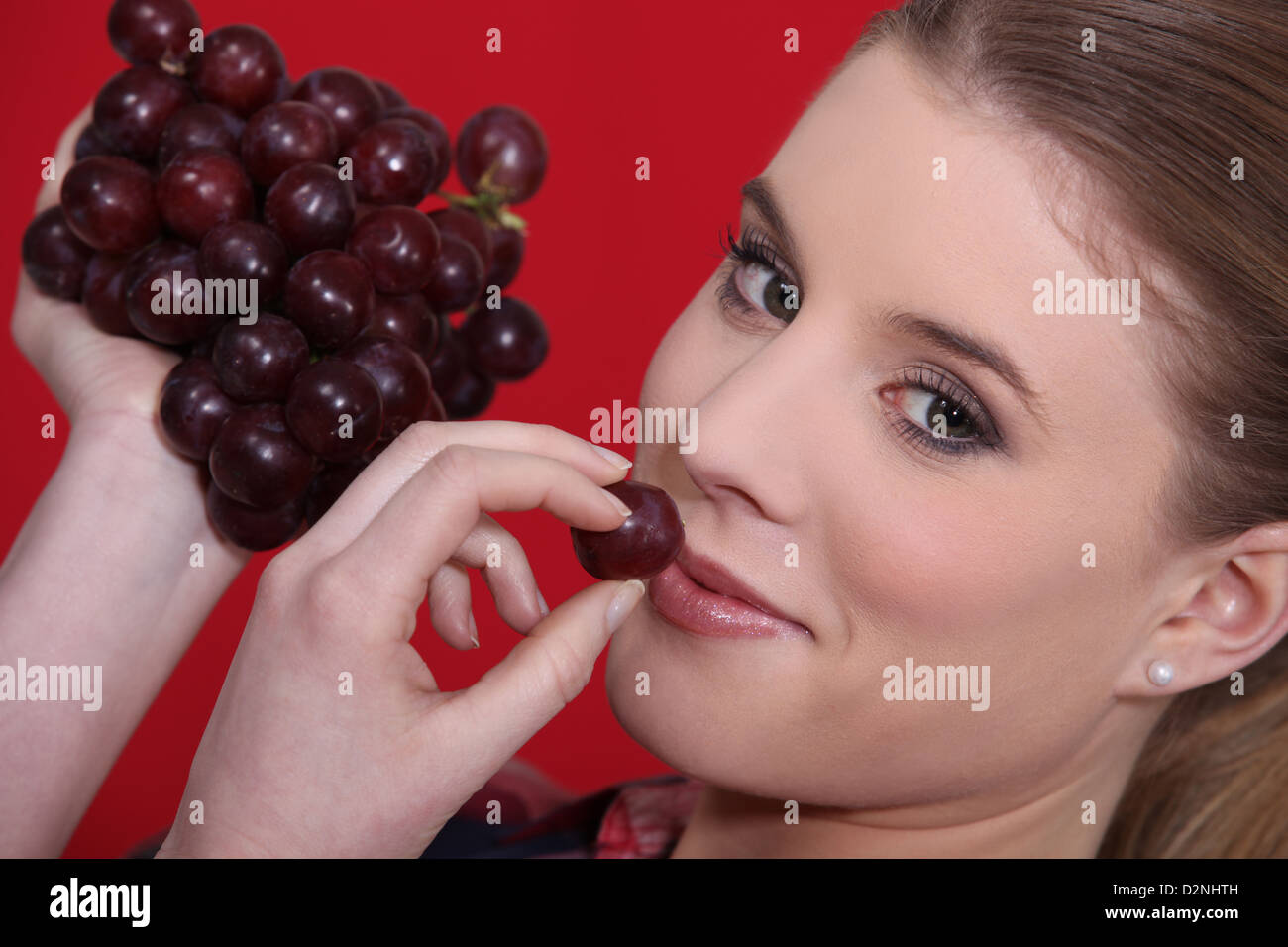 portrait of blonde eating red grapes Stock Photo - Alamy