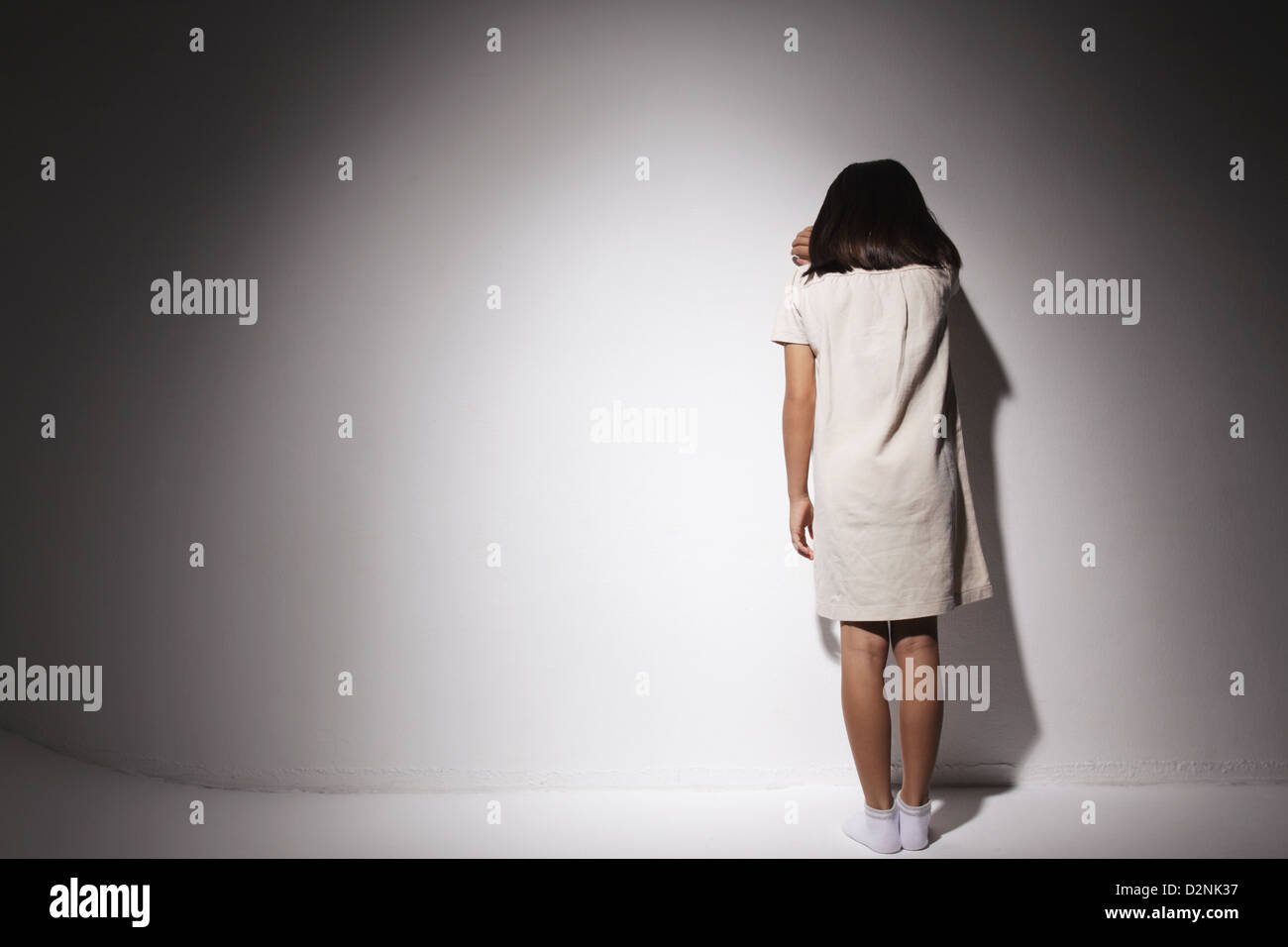 Girl in a white dress crying against a wall Stock Photo - Alamy